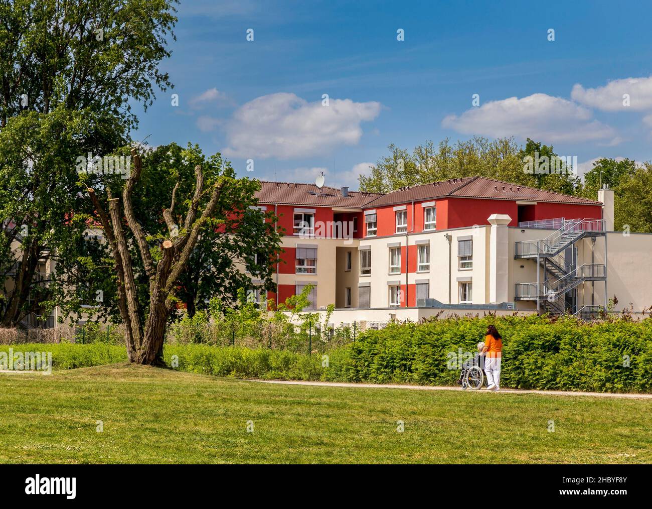 Carer with senior citizen in wheelchair in front of old people's home ...