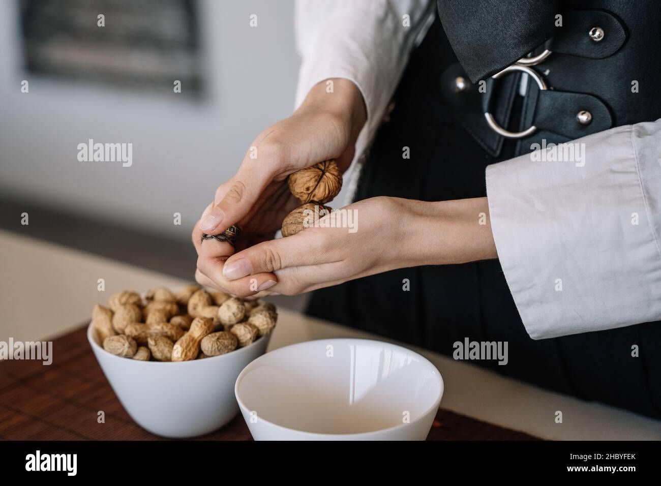 close-up view of a person cracking two walnuts with her hands, blurred ...
