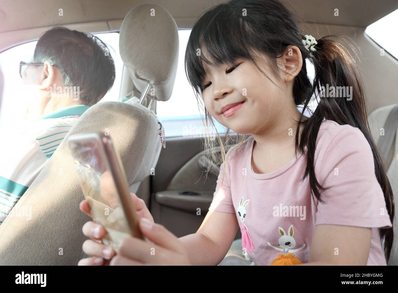 The Asian kid using mobile device in the car Stock Photo - Alamy