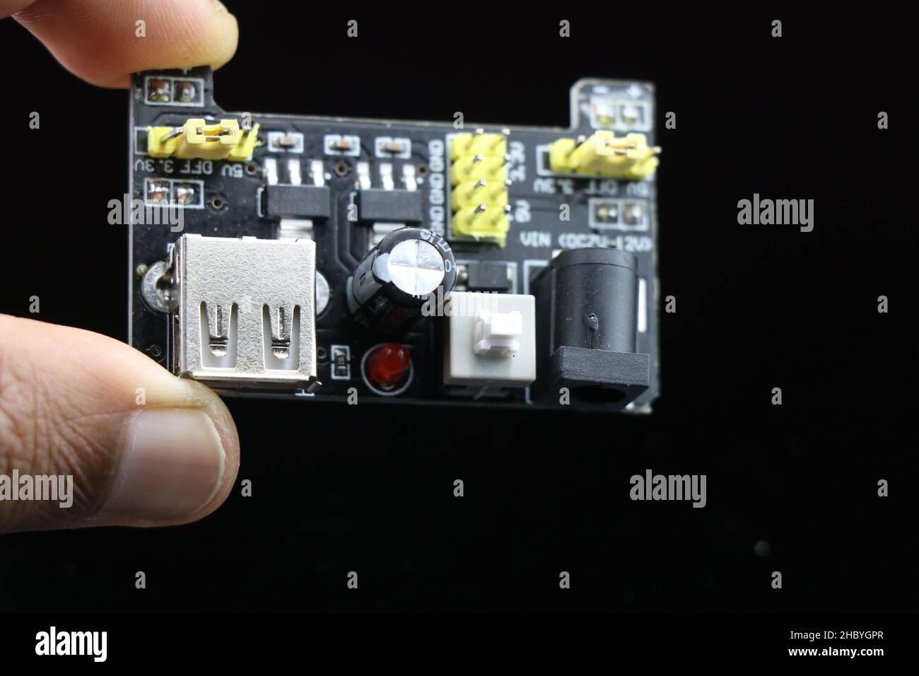 Breadboard power supply module held in hand isolated on black ...