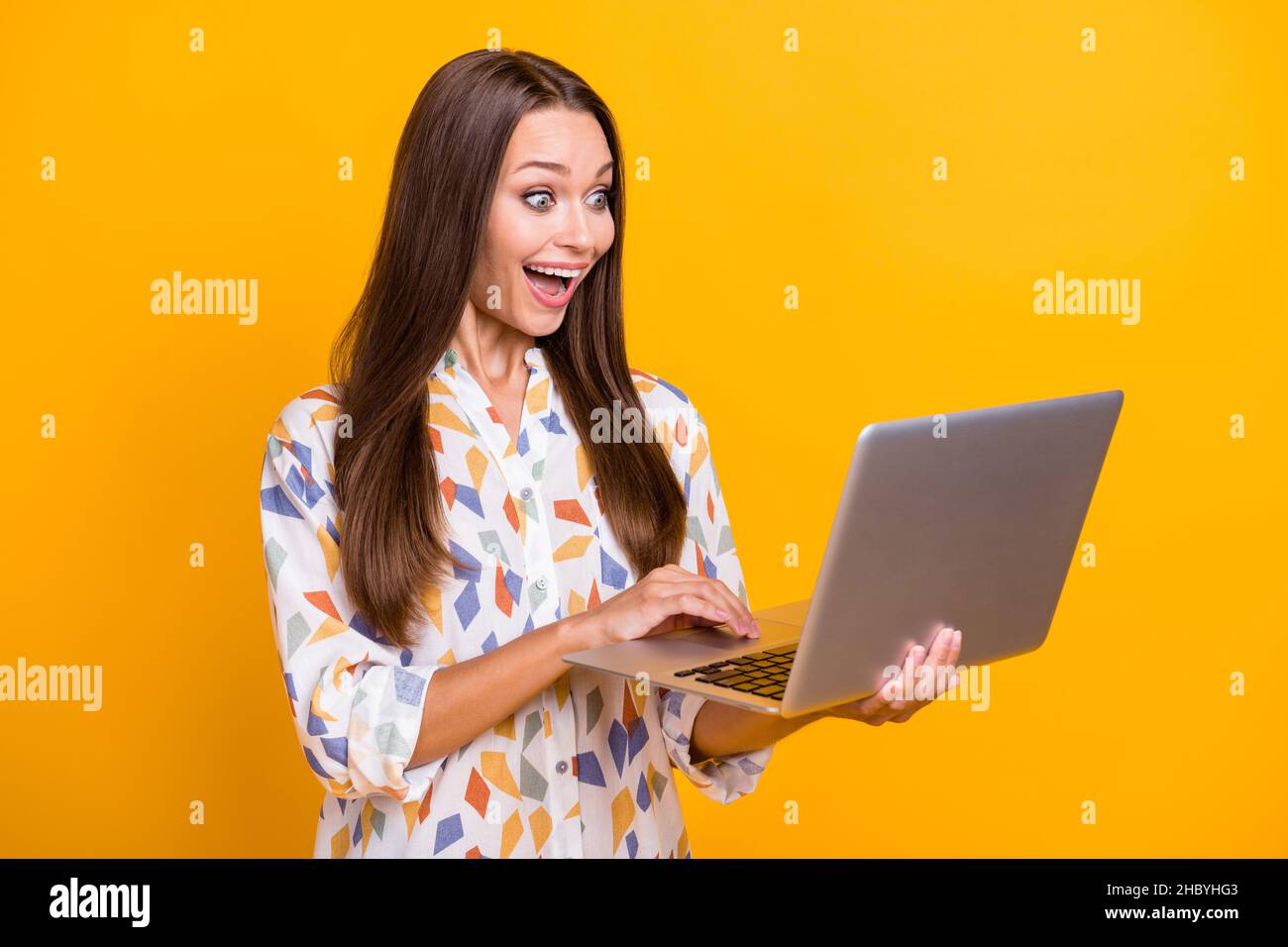 Photo portrait of excited girl browsing internet holding laptop ...