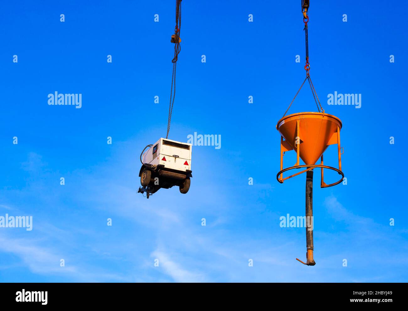 Construction machinery chained to a construction crane against a blue ...