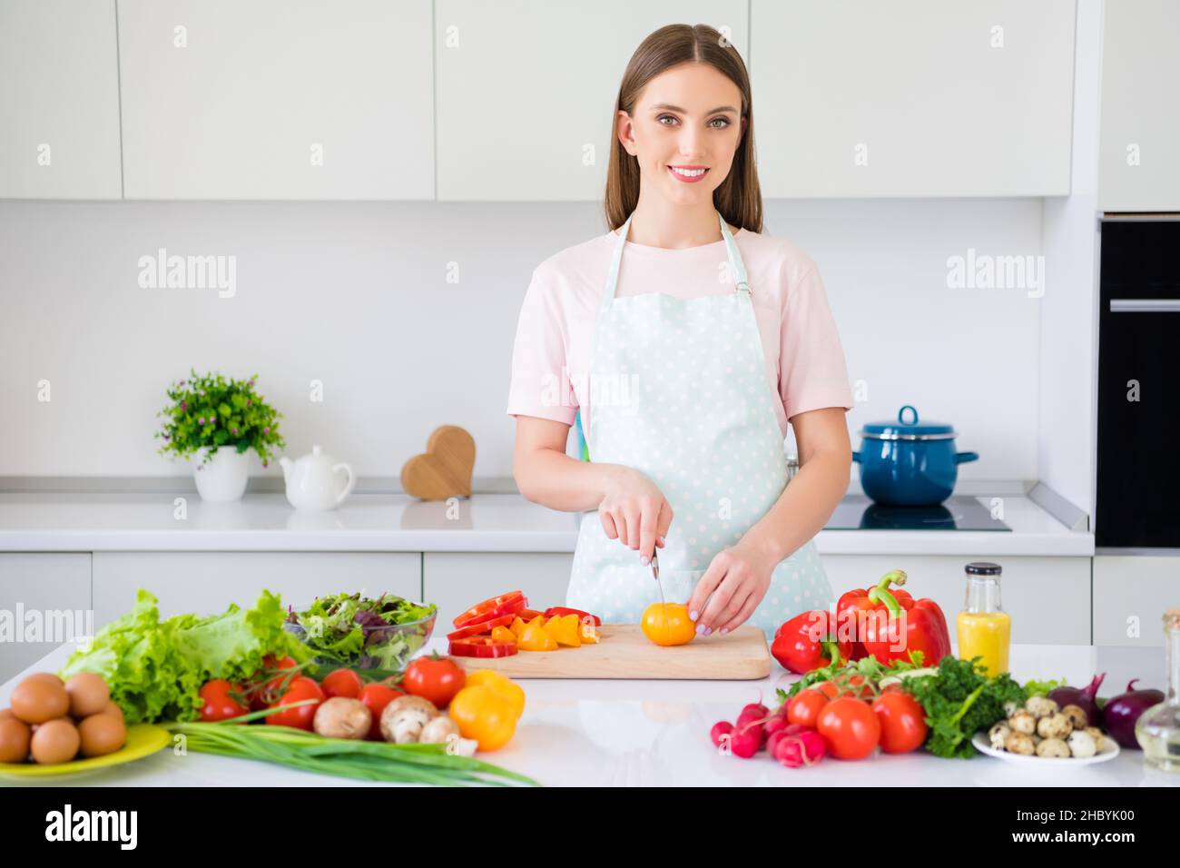 Portrait of attractive cheerful girl cutting tomato cooking fresh meal ...