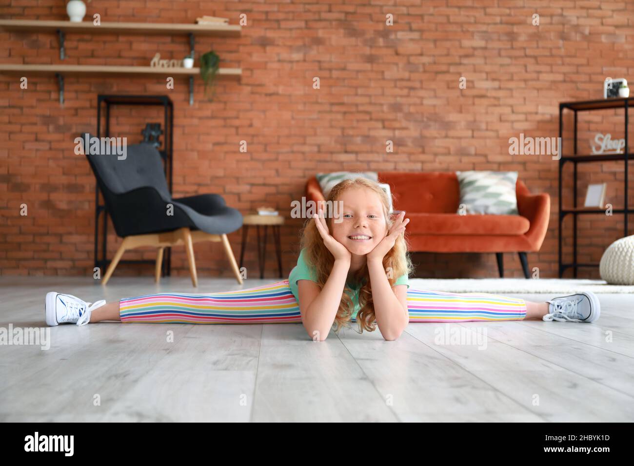 Little redhead girl in green t-shirt doing splits at home Stock Photo ...