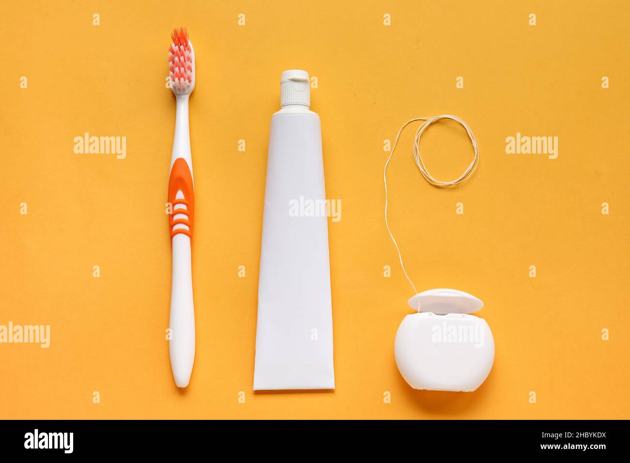 Dental floss with tooth paste and brush on orange background Stock ...