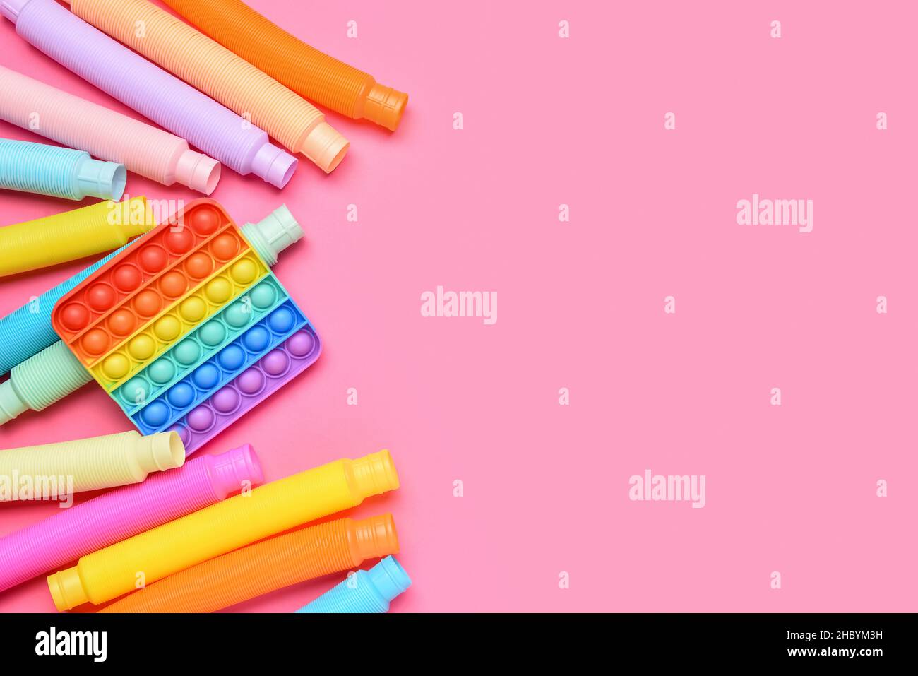 Colorful Pop Tubes and Pop it fidget toy on pink background Stock Photo ...