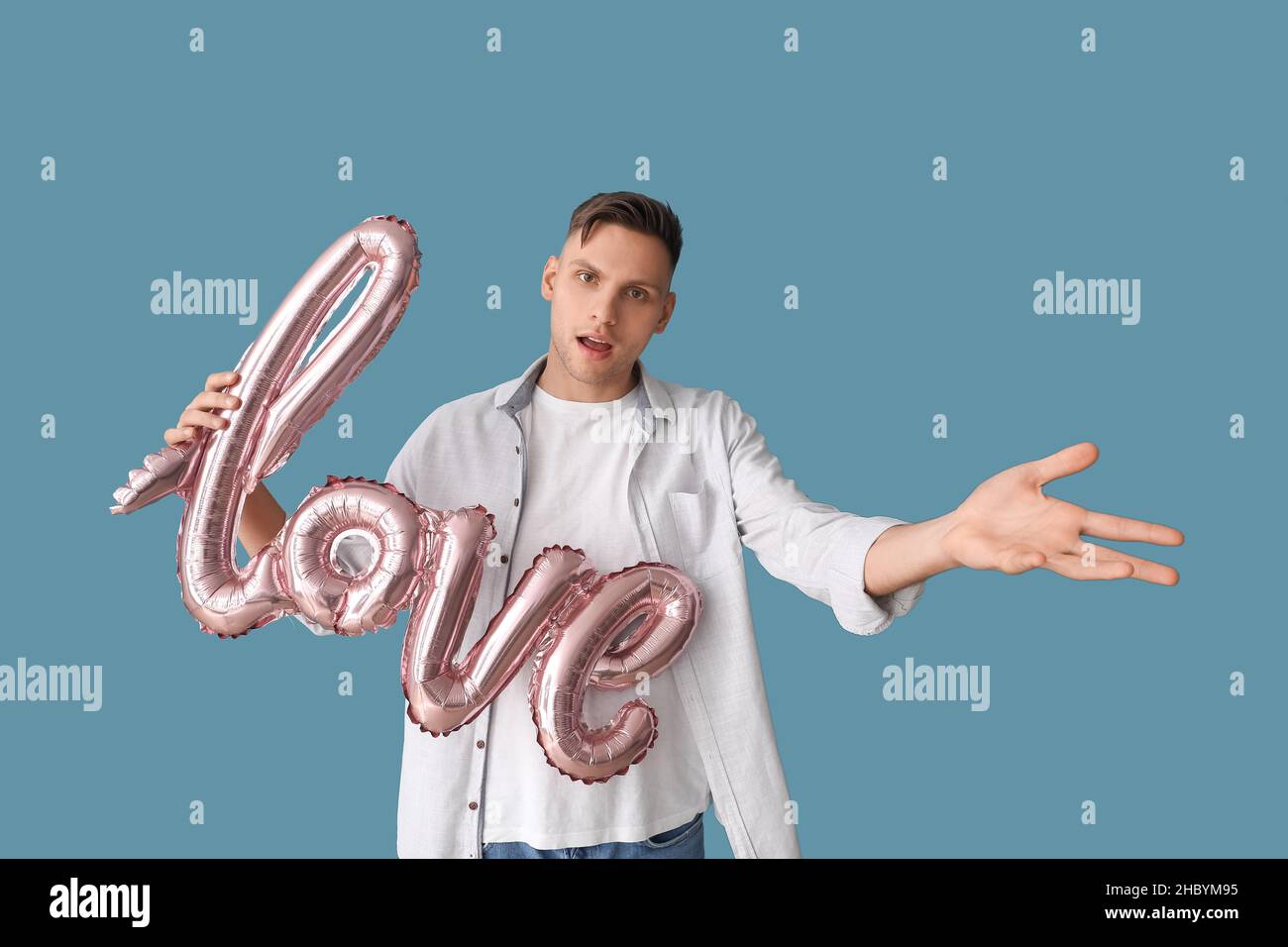 Confused man with balloon in shape of word LOVE on color background ...