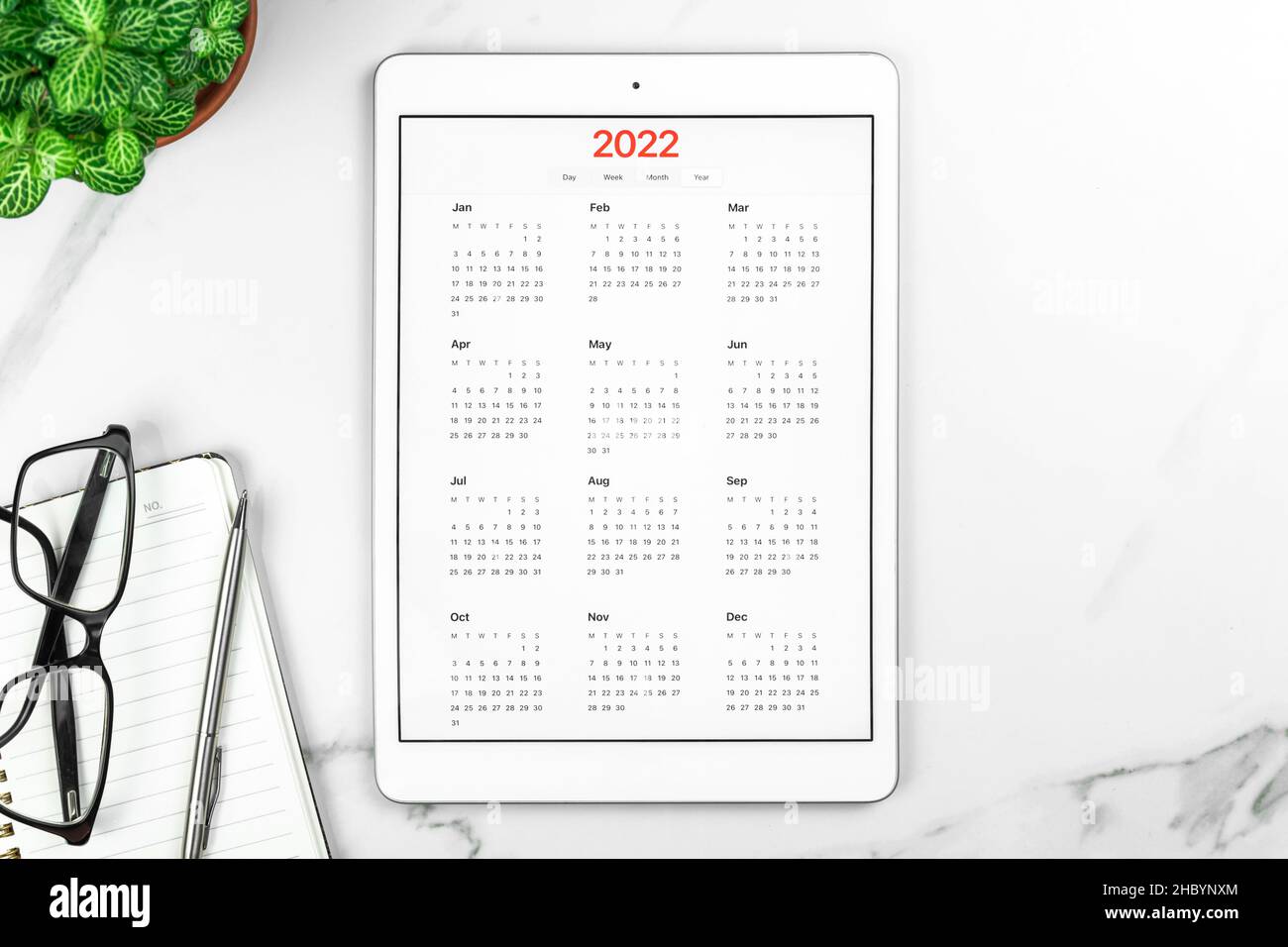 Calendar 2022. Tablet computer with open app. White marble background ...