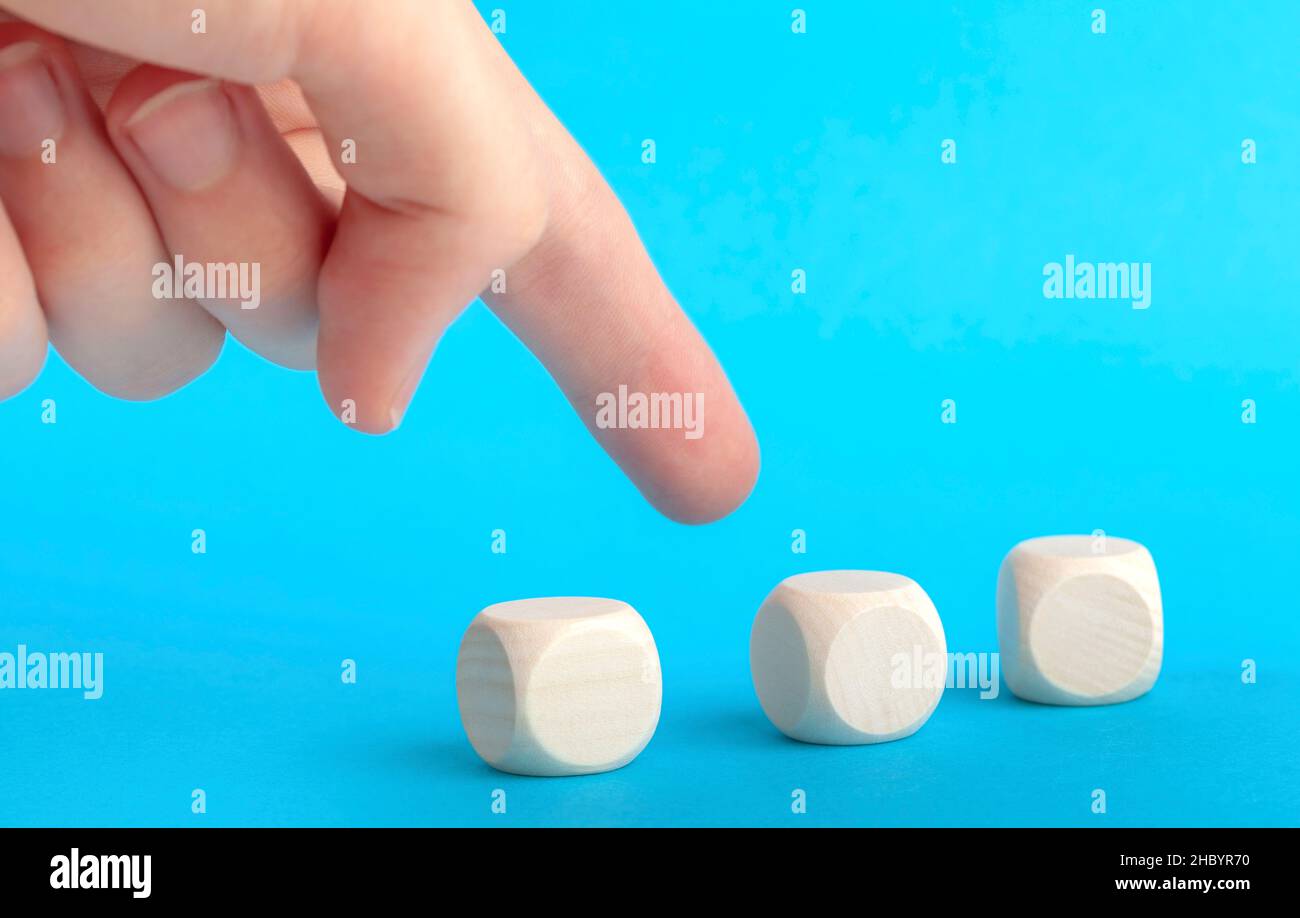 Finger pointing at one of three blank plain wooden blocks, group of ...