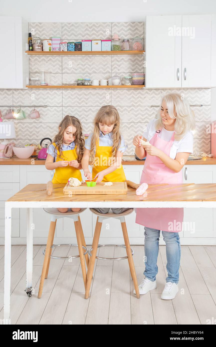Smiling caucasian mom teaching daughters to cook together in the ...