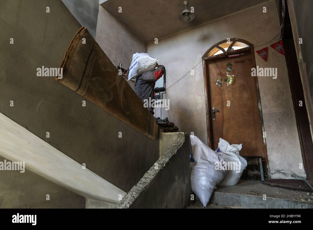 Palestinian workers place tar on the roof of a house to prevent ...
