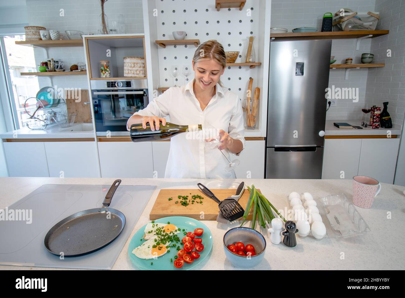 Beautiful blonde woman cooking in a modern equipped kitchen. Preparing ...