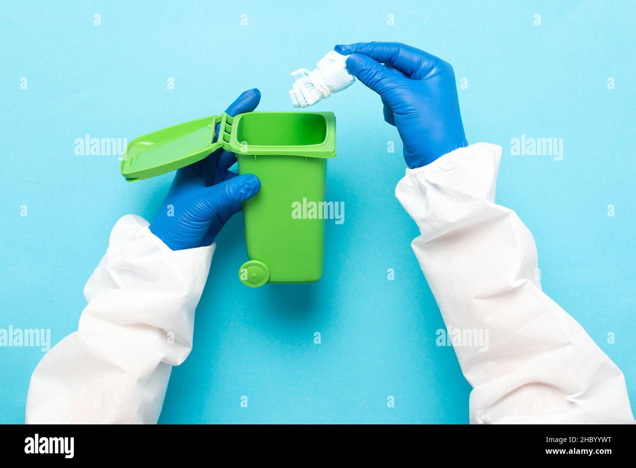 Throwing away a medical mask in a green container for recycling on a ...