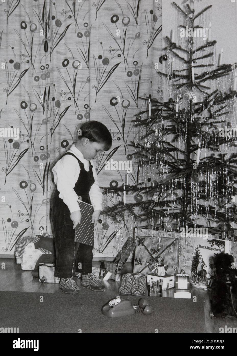 Christmas 1962 in Germany. A little boy is amazed and unwraps his ...
