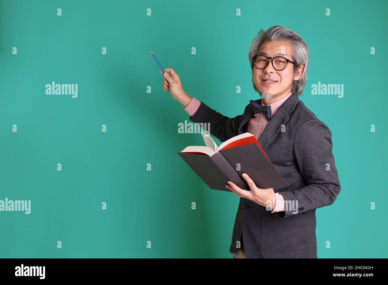 The senior Asian teacher standing on the green background Stock Photo ...