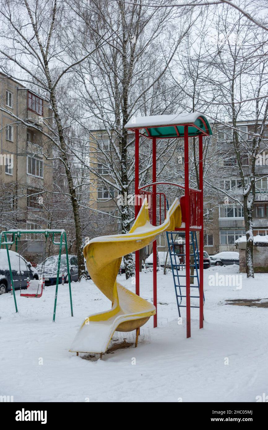 Snow-covered children's slide in the courtyard of a residential area ...