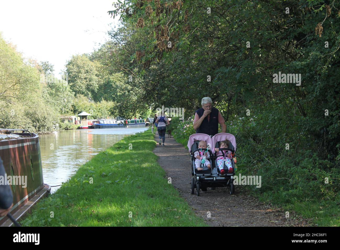 Mature man pushing a double buggy on the tow path. Grandad looking ...