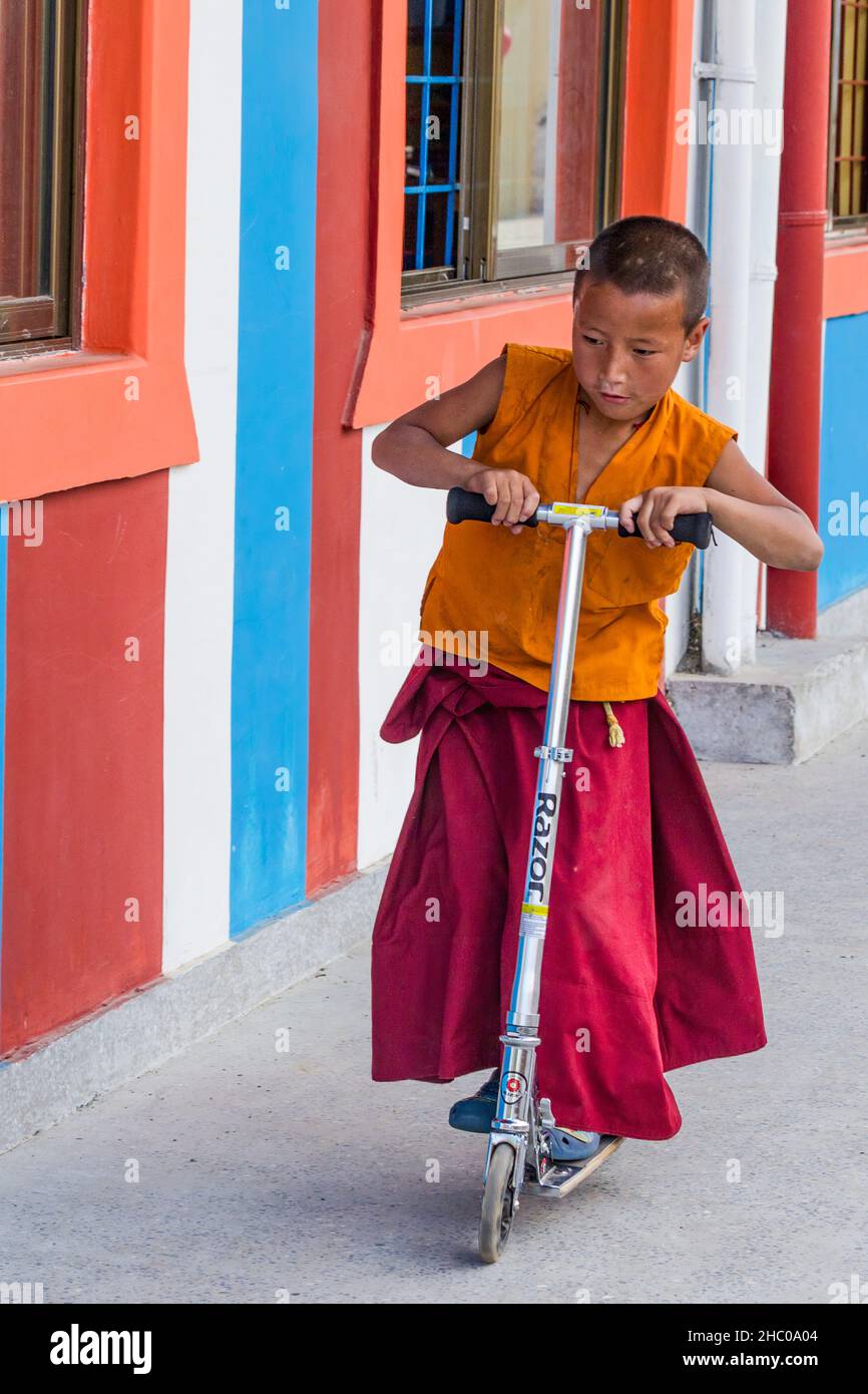 A young Buddhist monk riding a scooter at the Pema Tsal Sakya Monastery ...