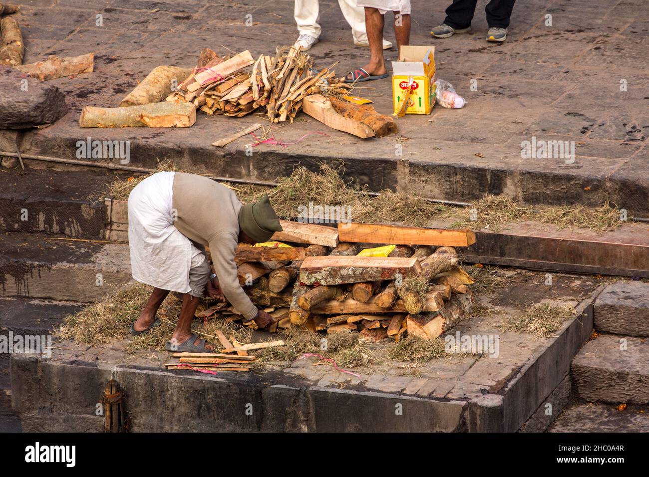 A worker stacks the wood for a funeral pyre at a ghat on the Bagmati ...