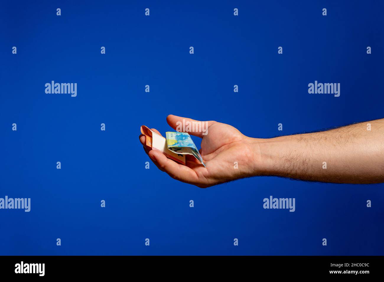 Man's hand offering folded euro bills on the palm of his hand, gesture ...