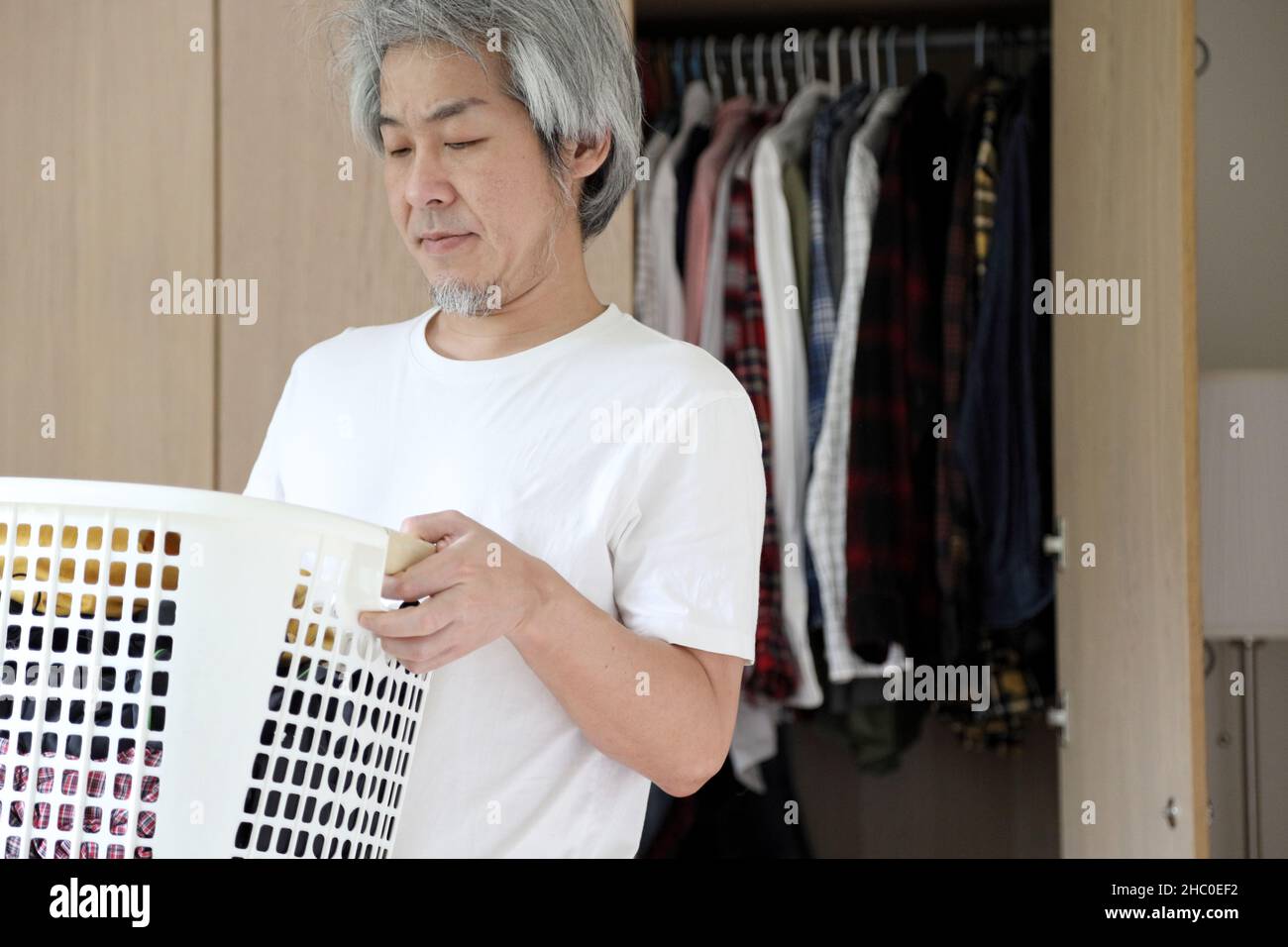 The Asian man carrying basket of clothes to do laundry Stock Photo - Alamy