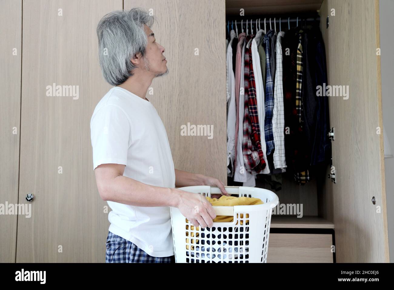 The Asian man carrying basket of clothes to do laundry Stock Photo - Alamy