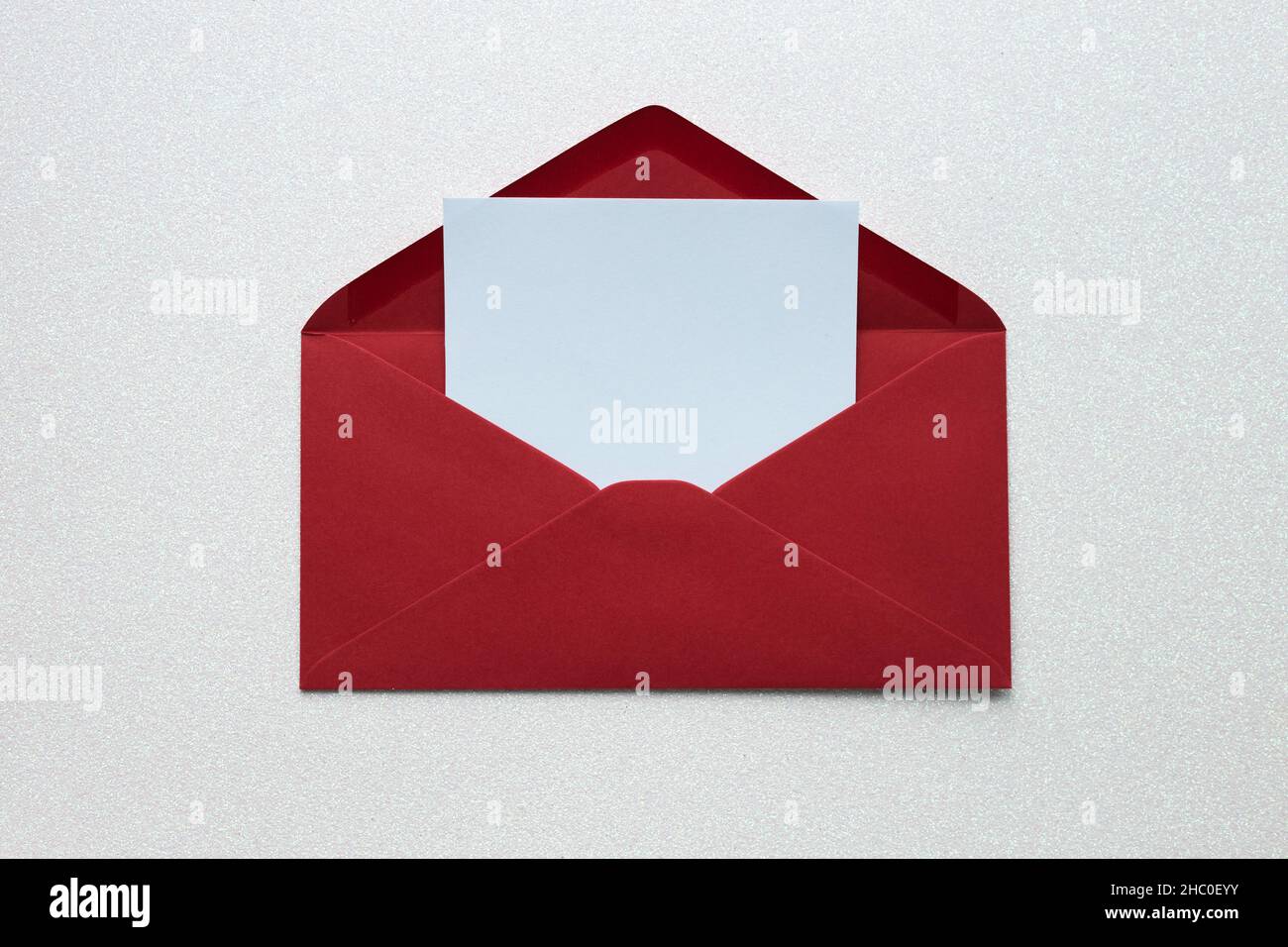 Open red envelope with blank writing paper extended on a silvery shiny ...