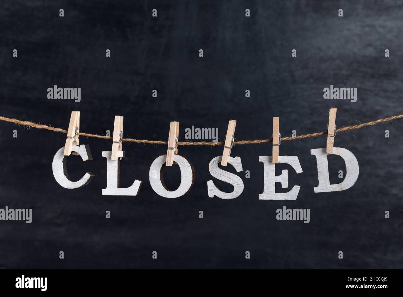 Word CLOSED held on a clothespin on a rope. Black background ...