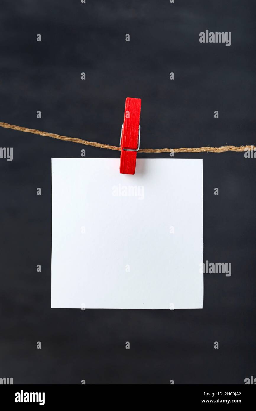 White blank note card hang with clothespin on rope. Black background ...