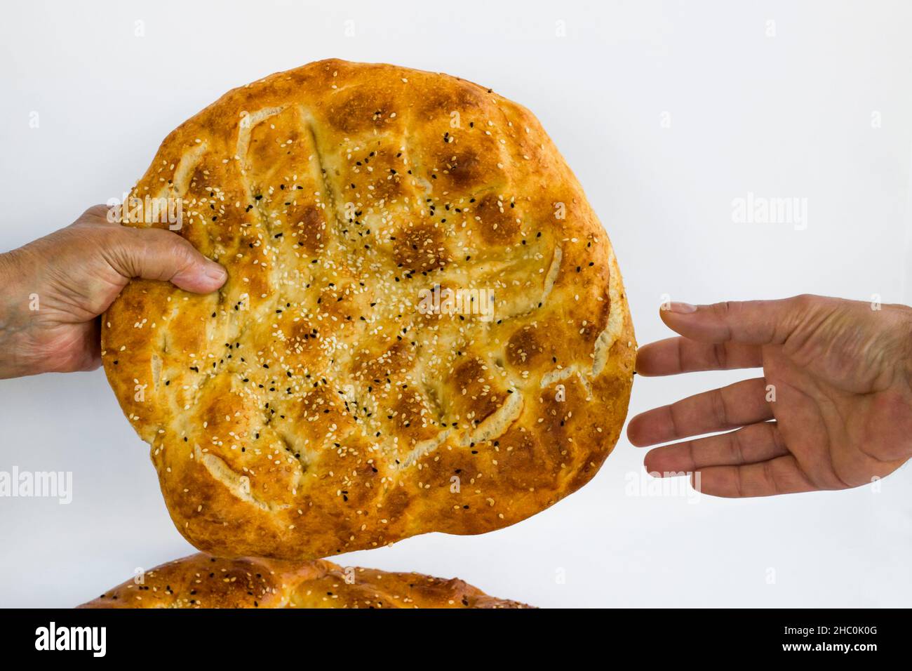 Two hands without gloves give ramadan bread to each other on white ...