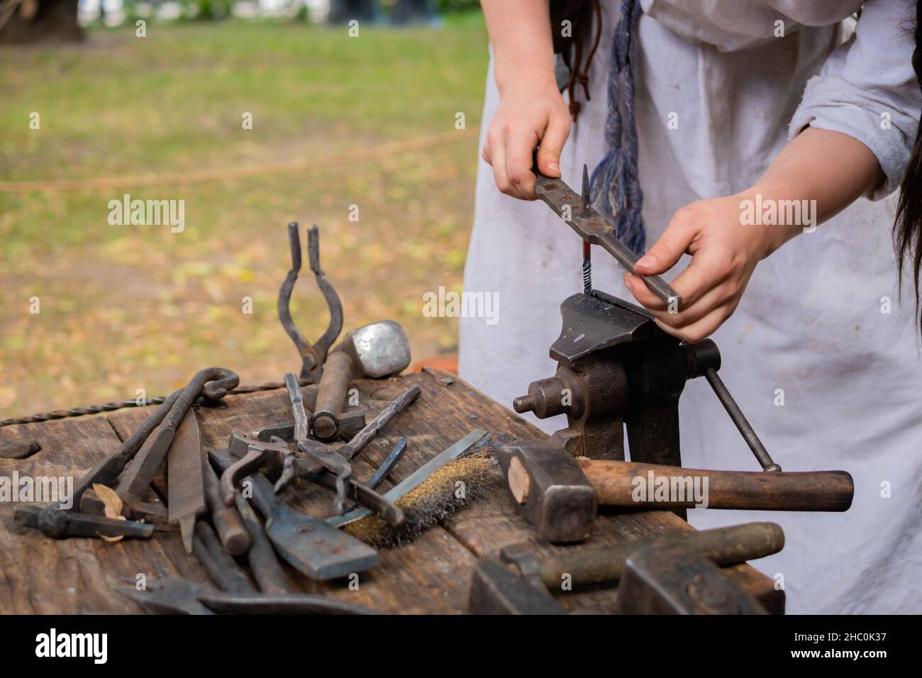 Professional blacksmith woman working with metal on anvil - close up ...