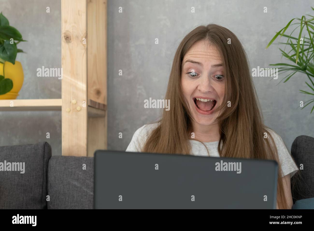 Very happy and surprised woman with laptop. Woman rejoices sitting at ...