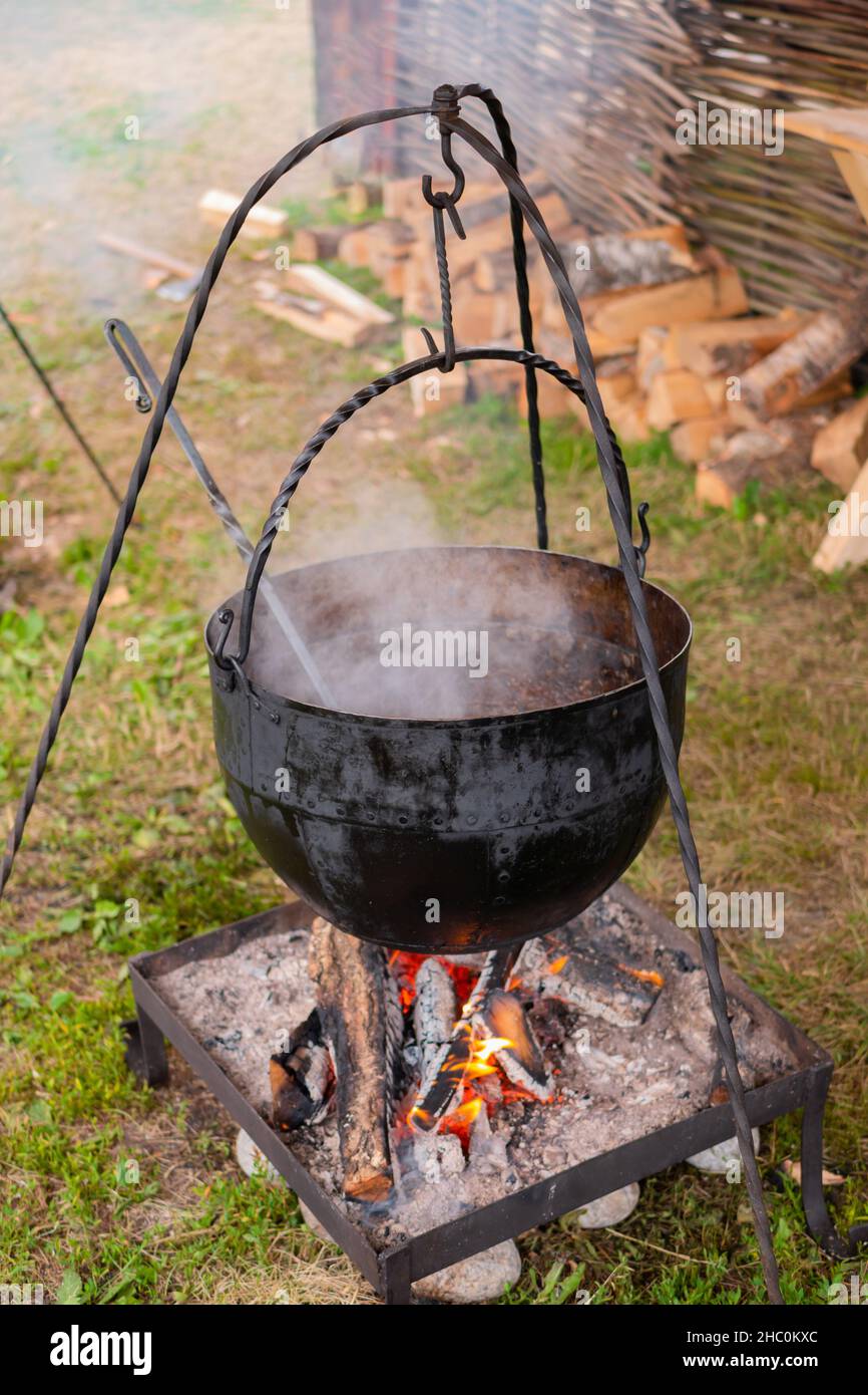 Preparing food in hanging pot over open fire - camping concept Stock ...