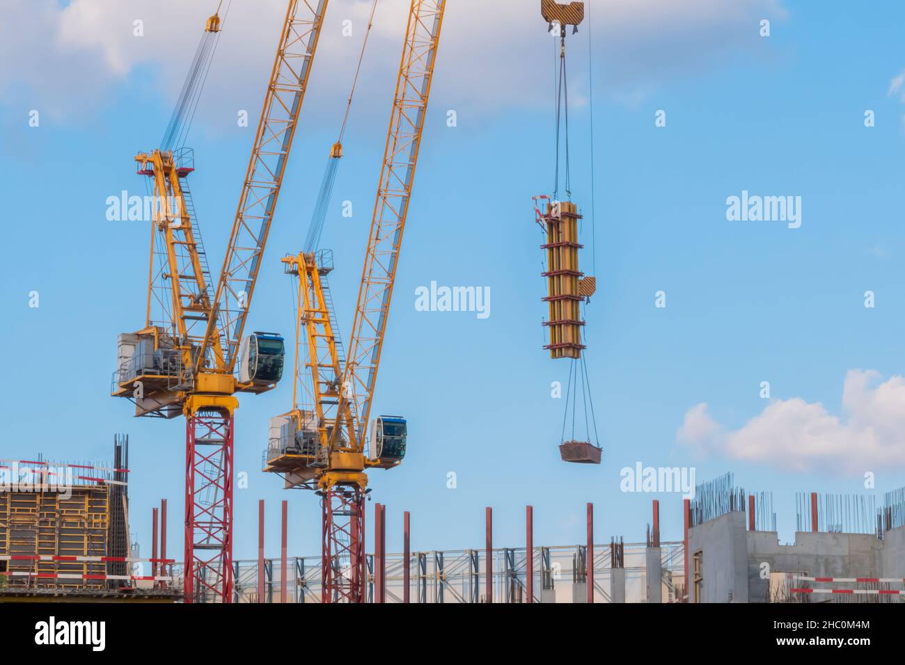 Two yellow tower cranes and unfinished building construction against ...