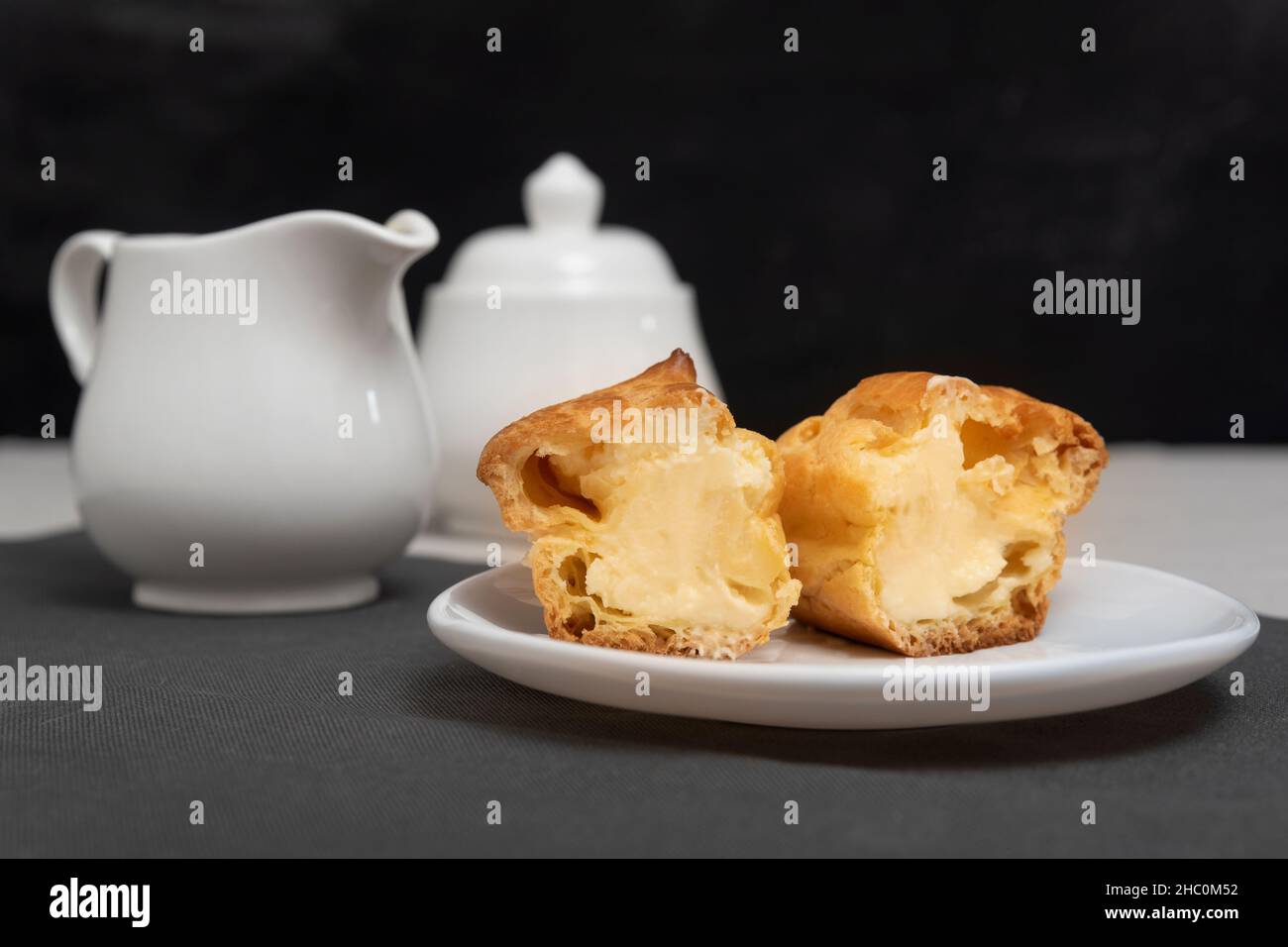 Cut homemade eclair with filling inside. Sweet pastries on the plate ...