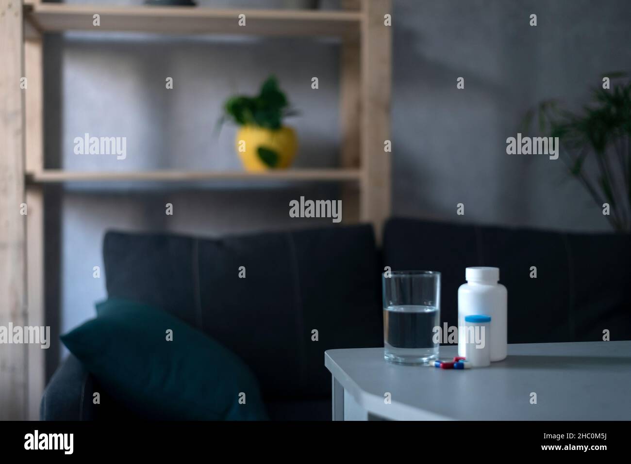 Glass of water and two bottle of pills on table in empty living room ...