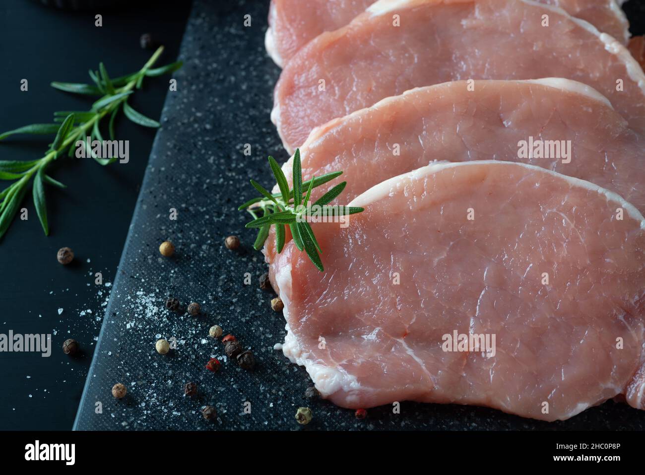 Raw sliced pork. Black background. Top view Stock Photo - Alamy