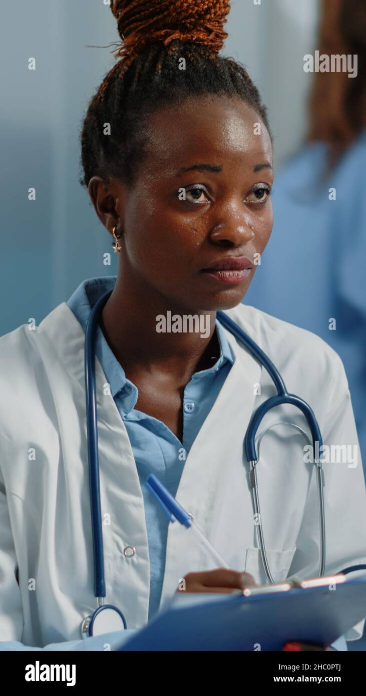 Close up of medic writing information on checkup papers for patient at ...