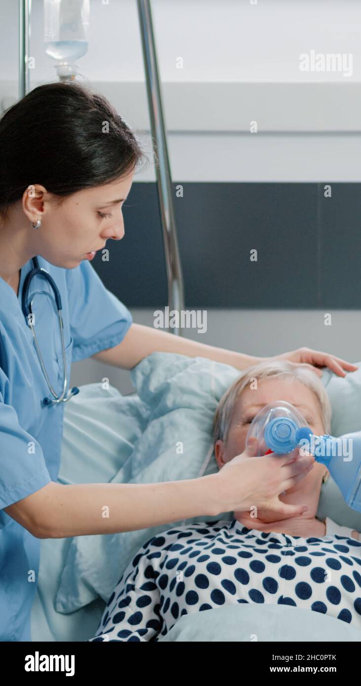 Sick woman asking for assistance from medical team in hospital ward bed ...