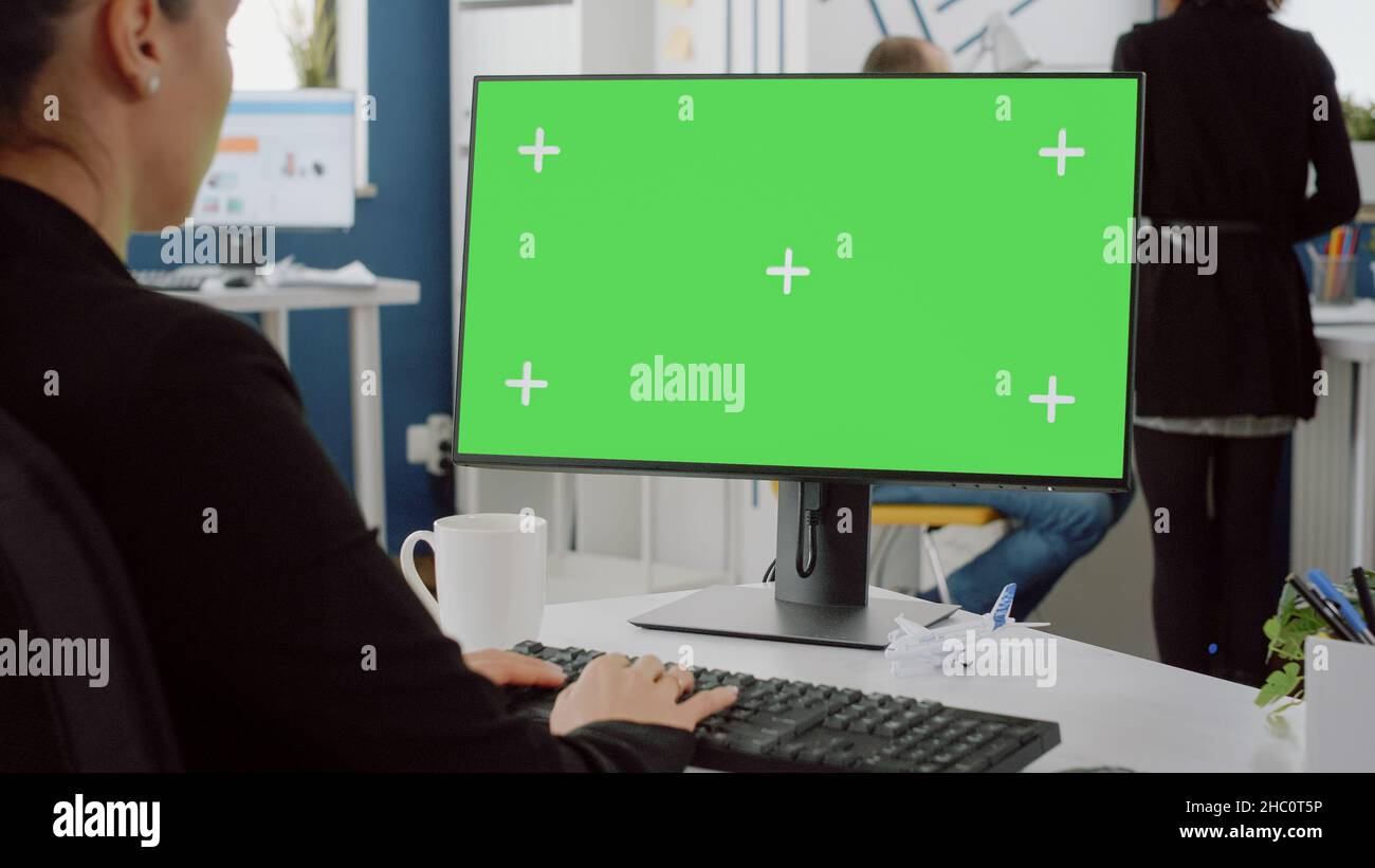 Close up of computer with horizontal green screen on desk. Woman with ...