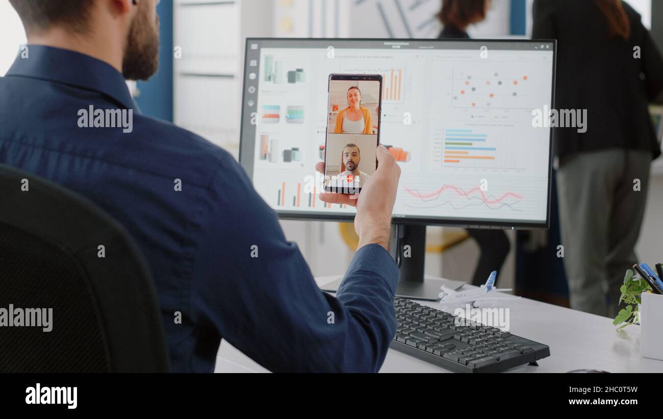 Corporate worker holding smartphone for video call conversation with ...