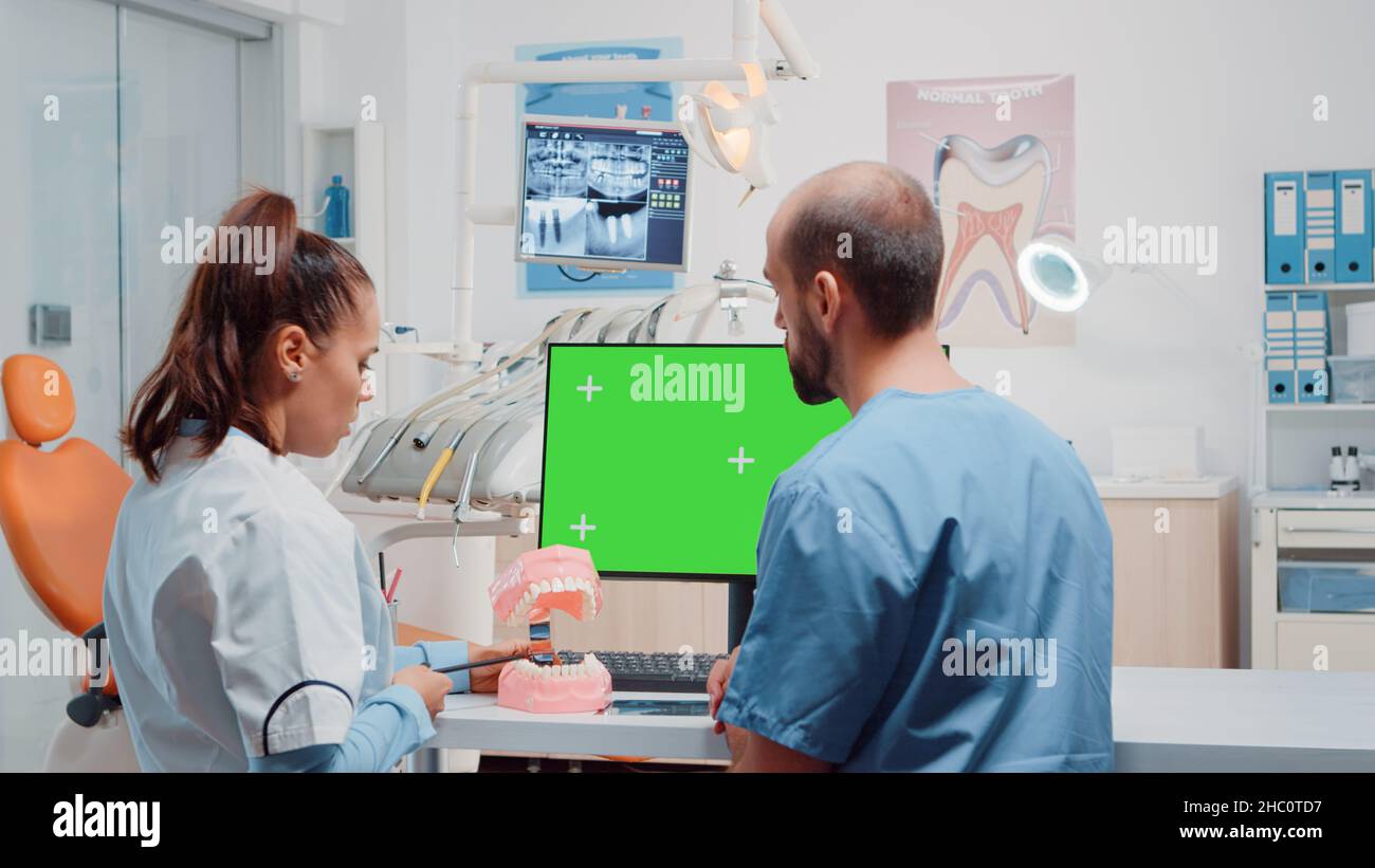 Woman dentist and man working with green screen on monitor while ...
