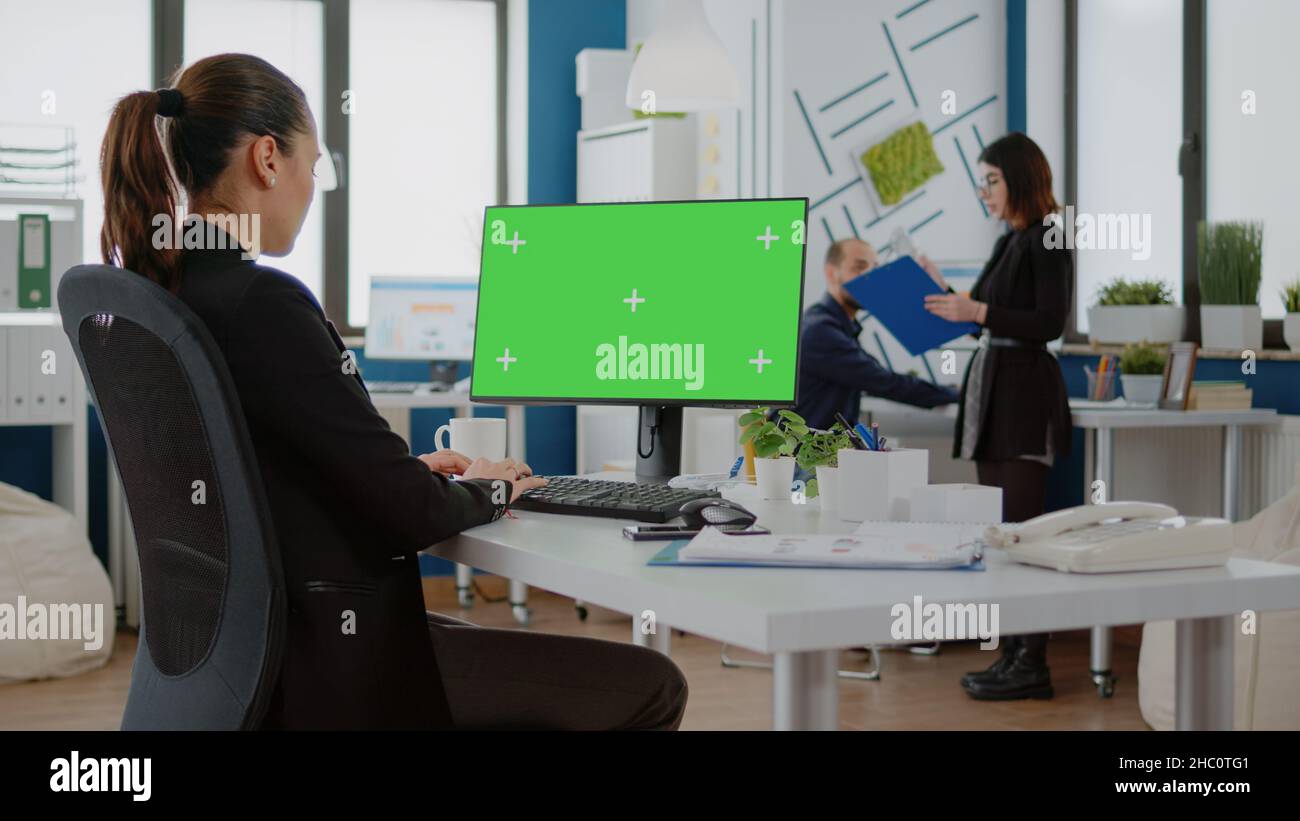 Businesswoman using computer with horizontal green screen at office ...
