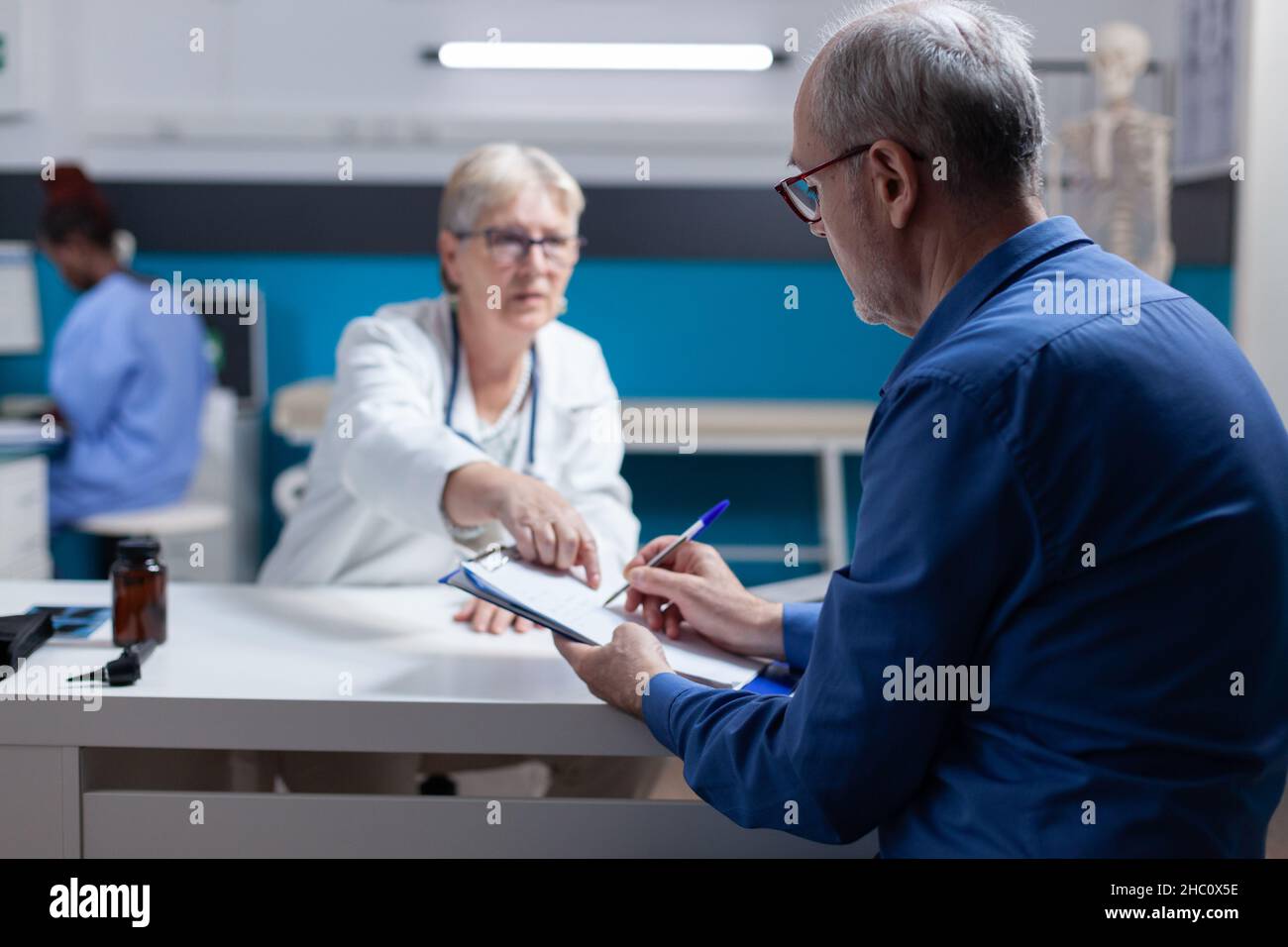 Senior patient signing appointment papers for doctor and healthcare ...