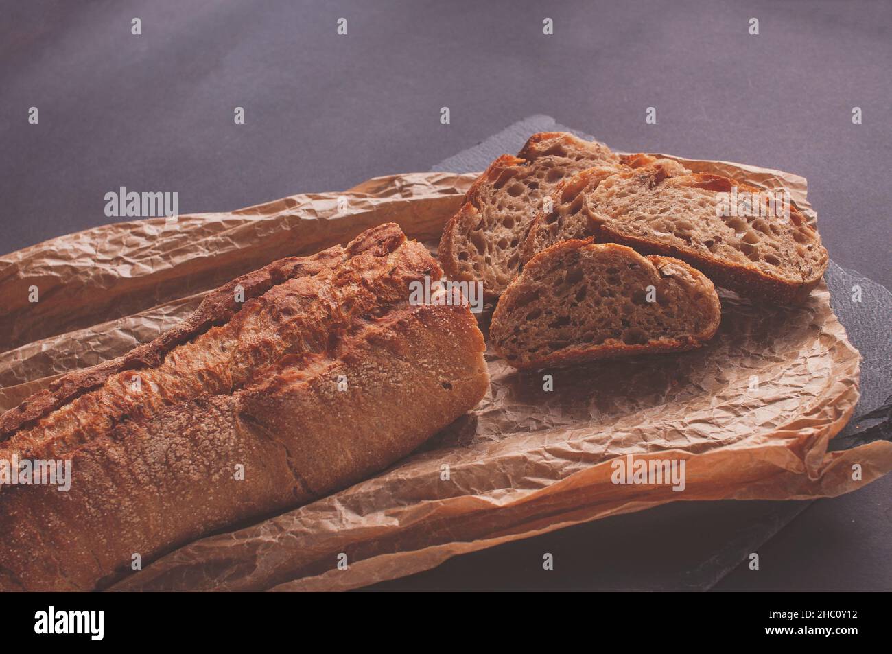 Rustic bread, beautiful golden crust, sliced bread lying on black board ...