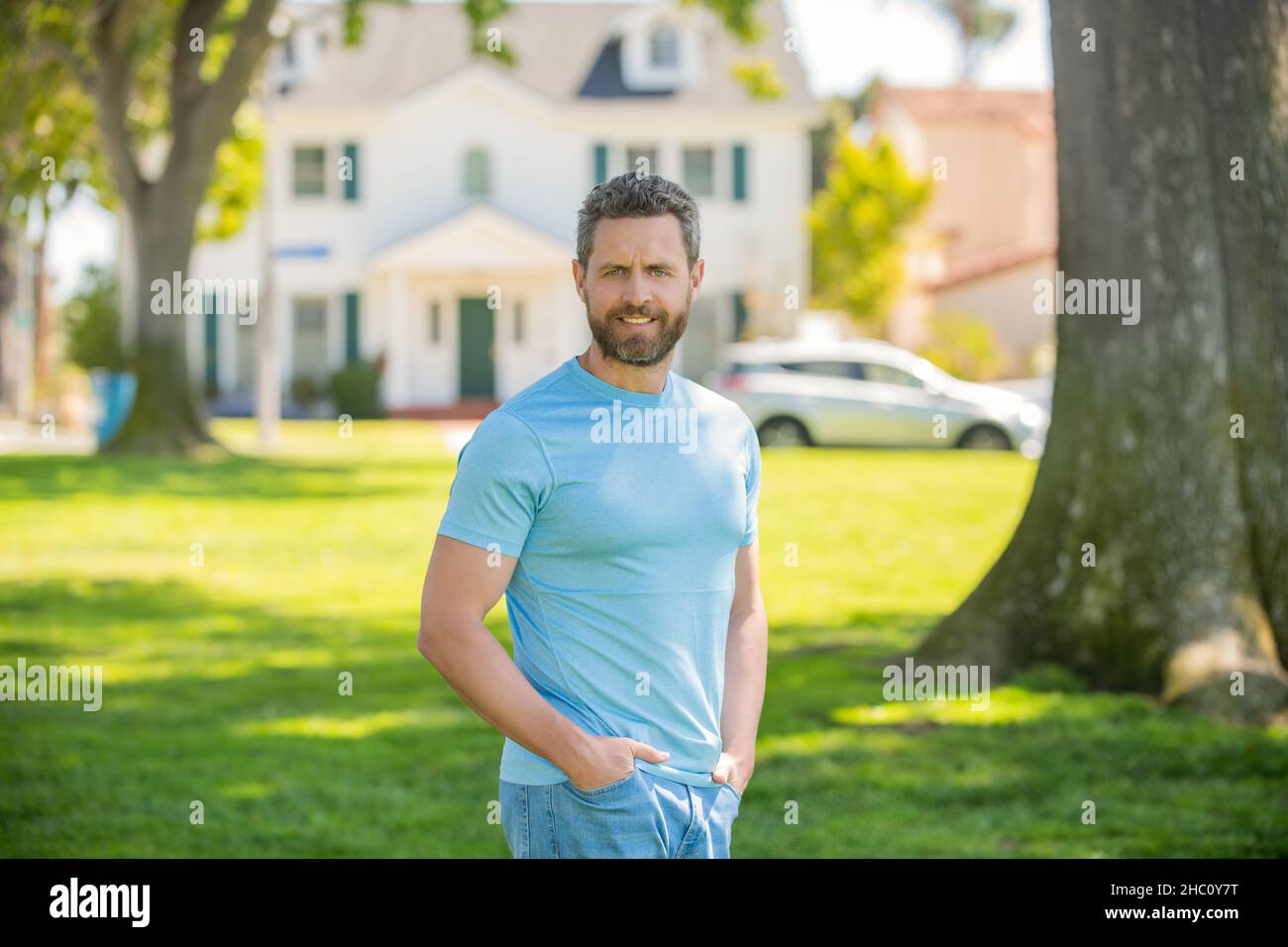 smiling unshaven guy standing near new house, realtor Stock Photo - Alamy
