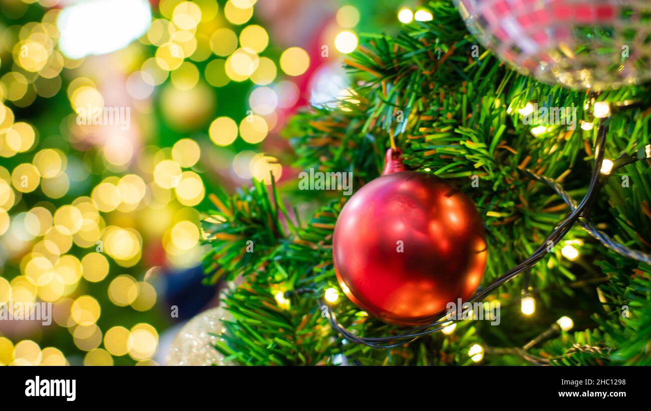 Christmas ball on pine tree brach with bokeh blurred of warm light ...