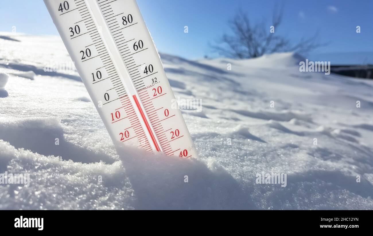 The thermometer in winter lies on the snow and shows low negative air ...