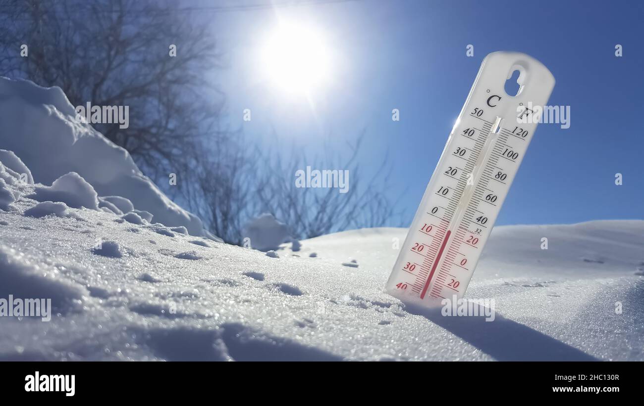 The thermometer in winter lies on the snow and shows low negative air ...