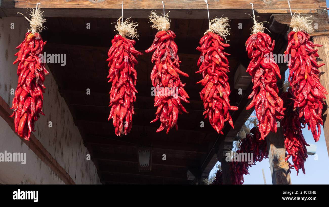 Multiple bunches of Chile Pepper Ristras hanging from a wooden beam in ...